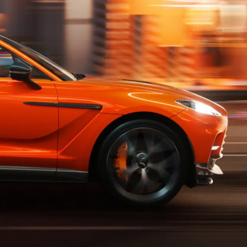 Side view of in motion orange Aston Martin DBX707